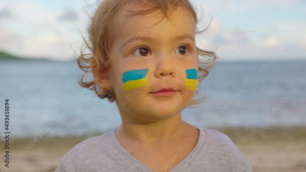 Close up portrait little baby with flag of Ukraine on face sitting ...