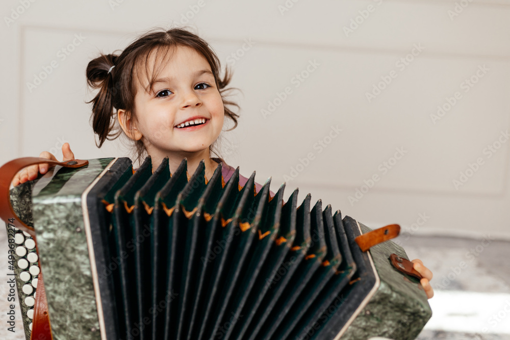 Little kid playing the accordion. Toddler girl learns how to play ...