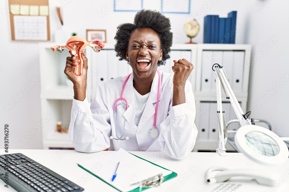 African doctor woman holding anatomical model of female genital organ ...