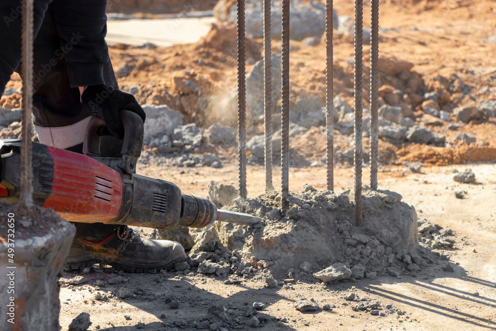 Foto de A worker with a jackhammer breaks concrete piles. Felling the ...