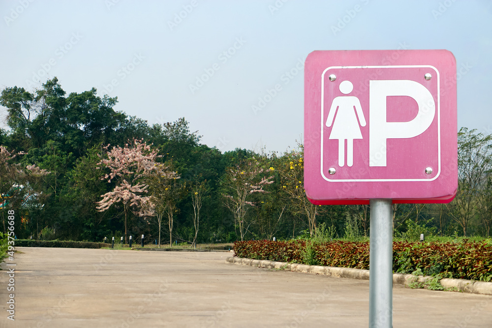 Traffic pink sign with symbol of lady and letter P at the public park ...