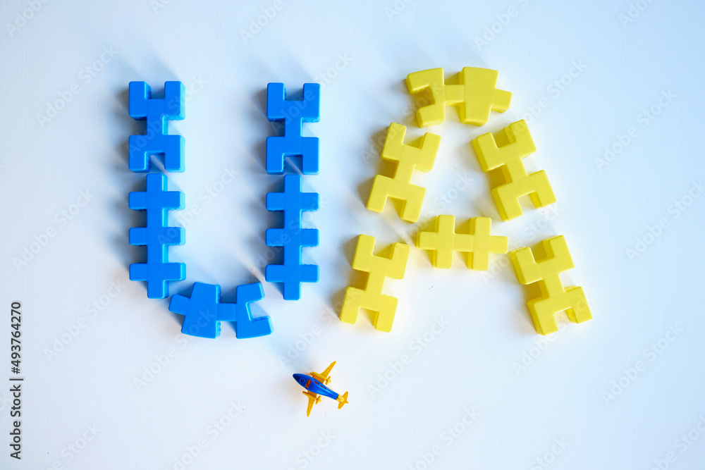 Puzzle letters UA blue-yellow color and a small toy plane on a light ...