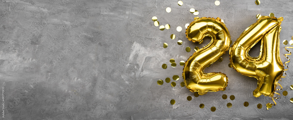 Yellow foil balloon number, number twenty-four on a concrete background ...