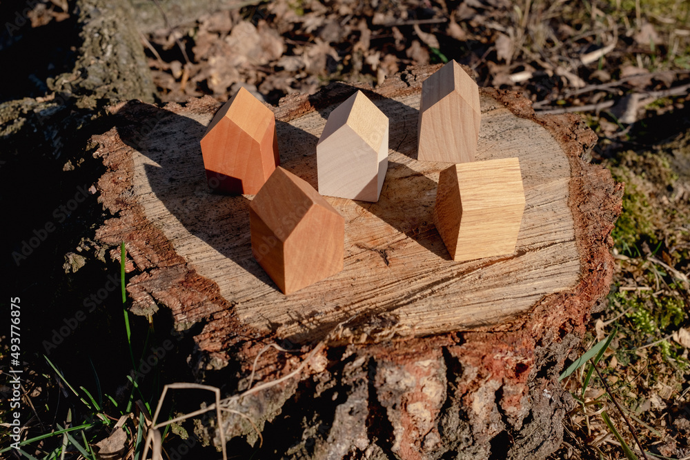 wooden house models on tree stump in the outdoors. concept image for ...