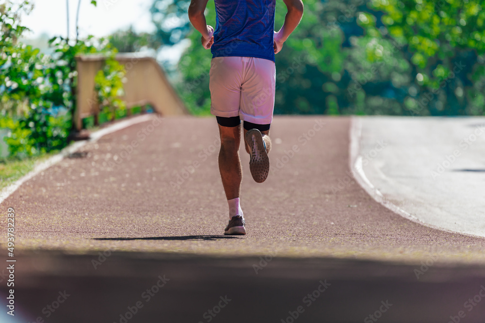 Athletic young man running on the race track in a sports park Stock ...