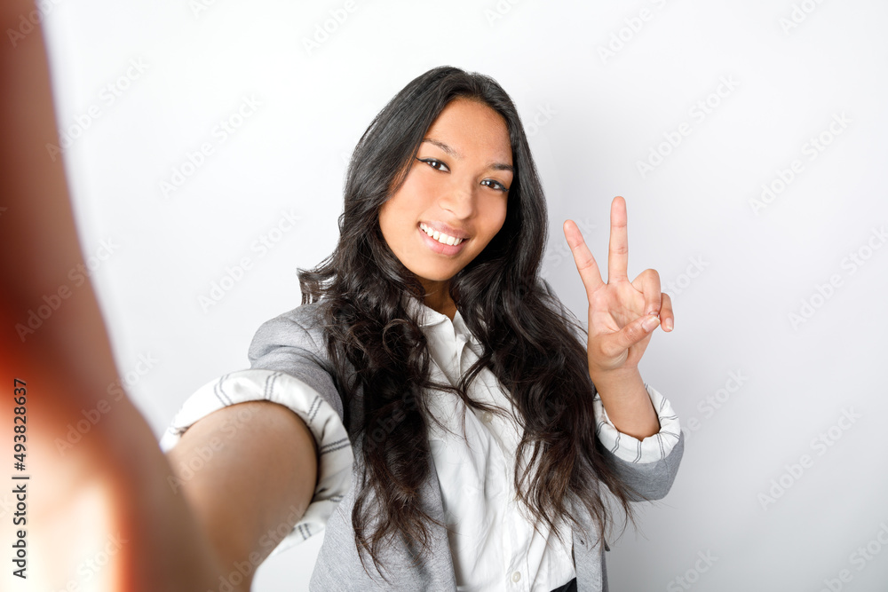 Beautiful woman taking a selfie rising two fingers. Victory symbol self ...
