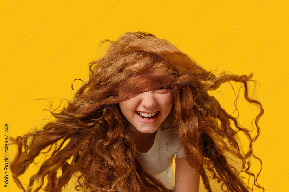 Cute girl with airy hair showing white teeth on yellow background ...