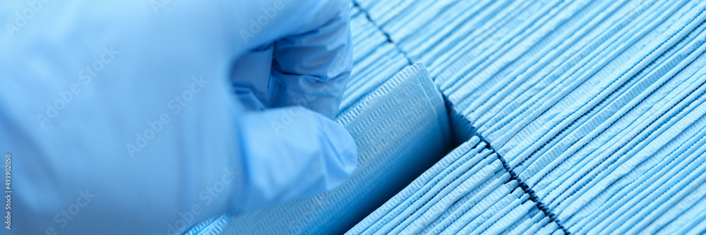 Nurse wearing protective rubber gloves pulling out sterile blue medical ...