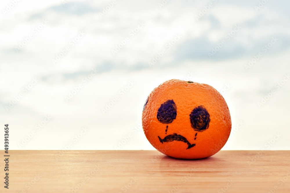 Orange with black eyes, sad and sad crying tears flowing on the wooden ...