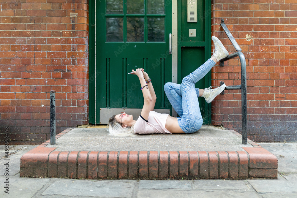 Teenager using smart phone lying in front of entrance Stock Photo ...