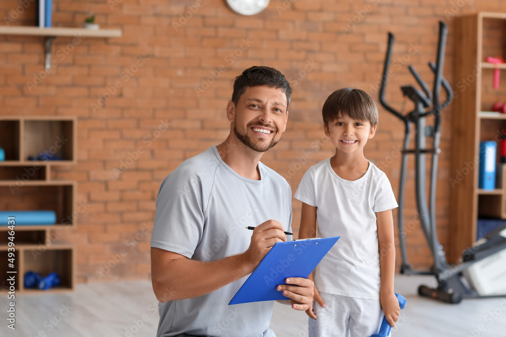 Male coach with his little trainee writing in clipboard at gym Stock ...