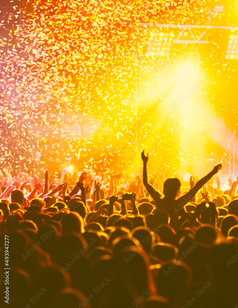 A crowded concert hall with scene stage orange and yellow lights, rock ...