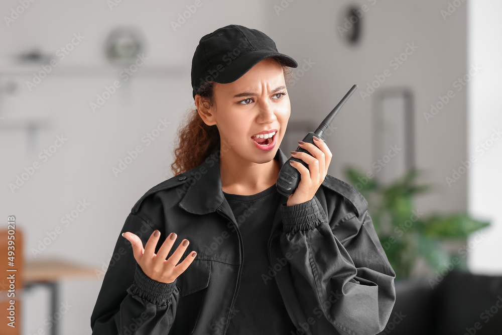 Angry African-American female security guard with radio transmitter in ...