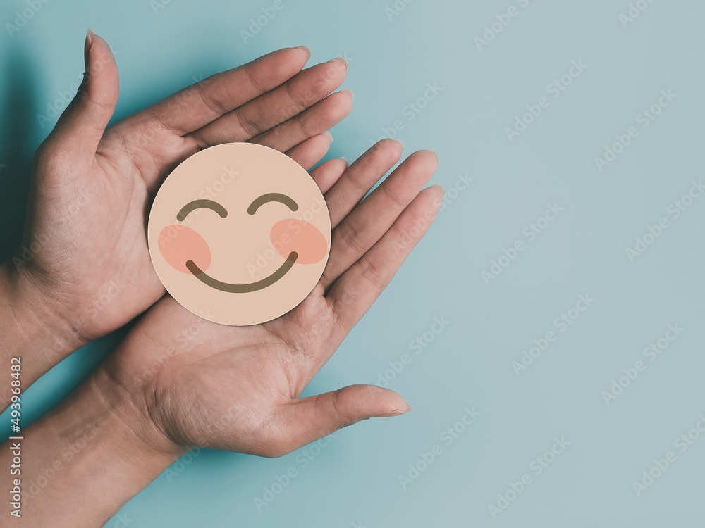 Hand holding green paper cut happy smile face on green background ...