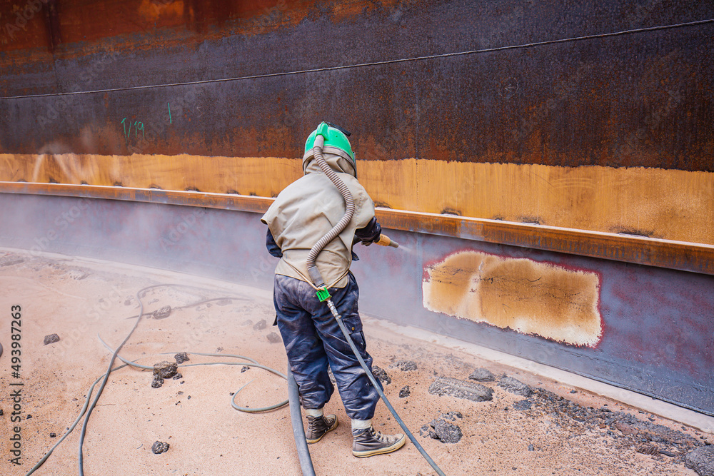 Female worker surface corrosion plate preparation by sand blasting ...