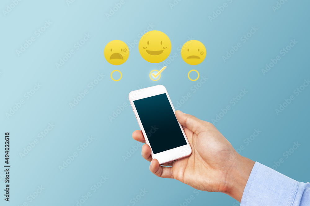 Customer holding smartphone or mobile phone with rating feedback scale ...