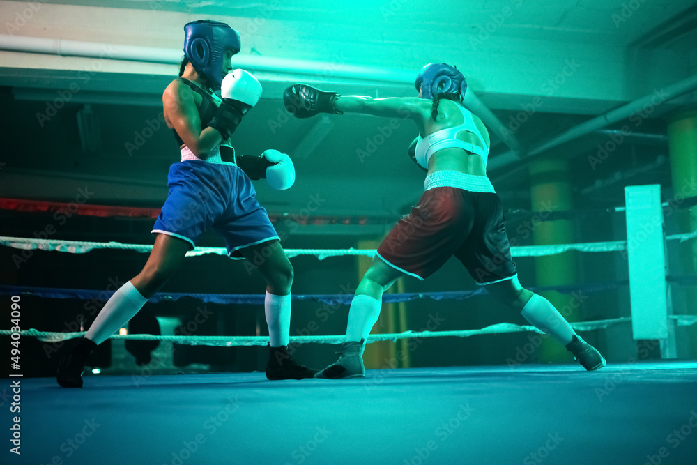Sporty female boxers improving punches on ring. Two girls in sportswear ...