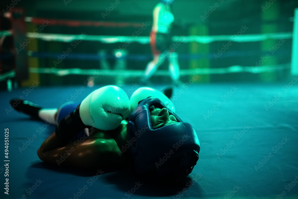 Close-up of female boxer knocked out in final round. Two young girls boxing on ring and one girl ...