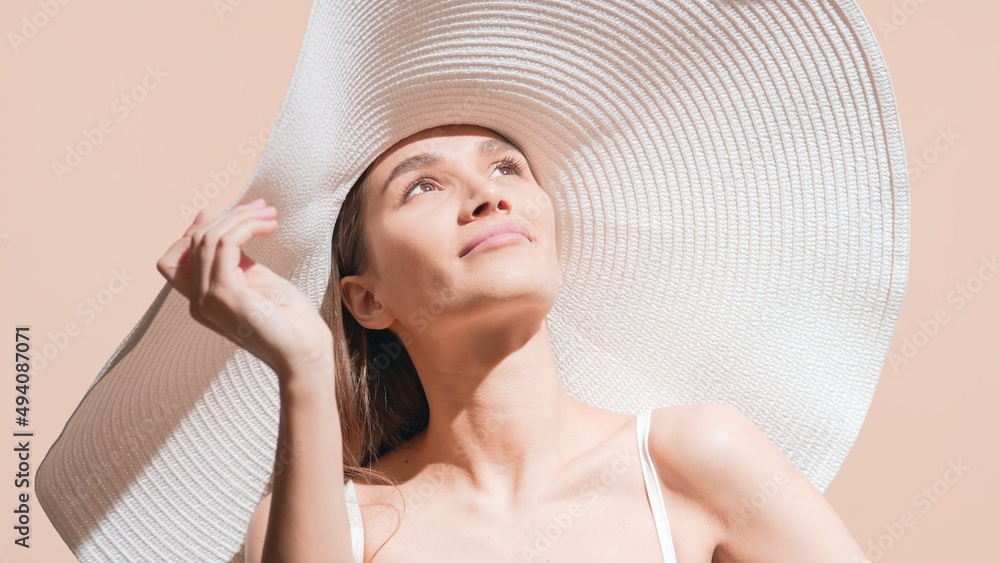 Young brunette Caucasian woman in a big white hat enjoys the sun ...