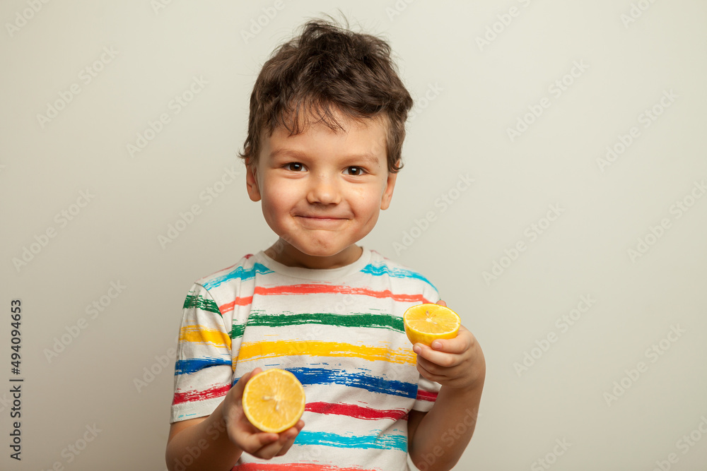 little boy eating lemon, sour taste, makes grimace, facial emotions ...