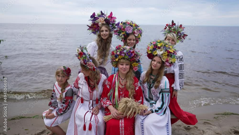 Group of Ukrainian young women and girl sitting on sandy river beach ...