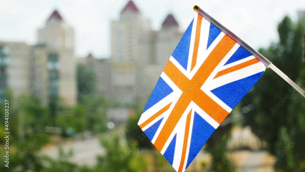 Flag of the United Kingdom set against blue sky, city street and ...