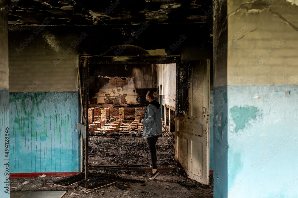 Destroyed building. Burnt building . Broken windows with ash . Woman in ...