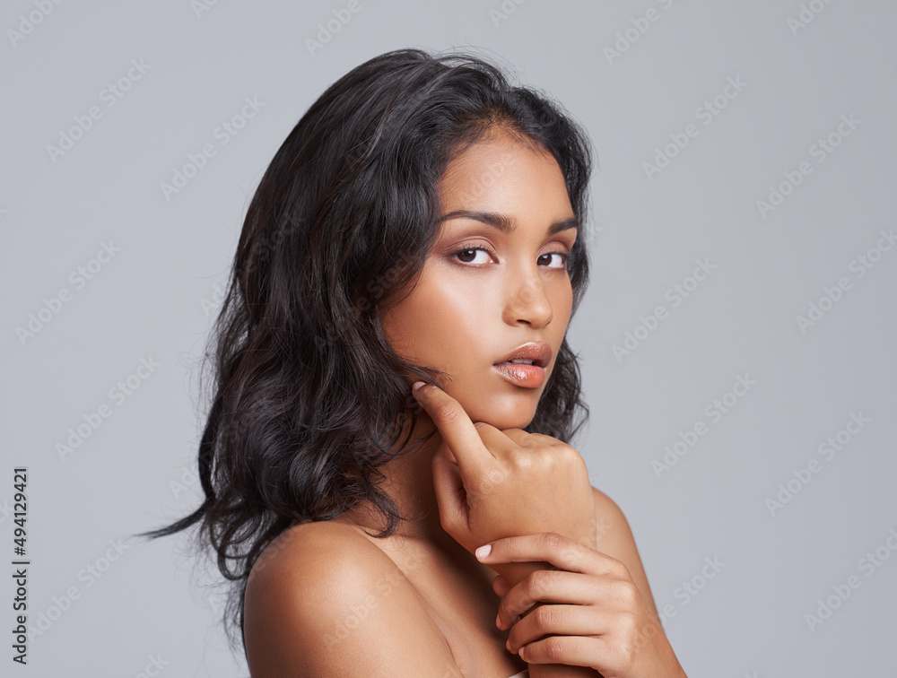 All natural beauty. Shot of a beautiful young posing over a gray ...