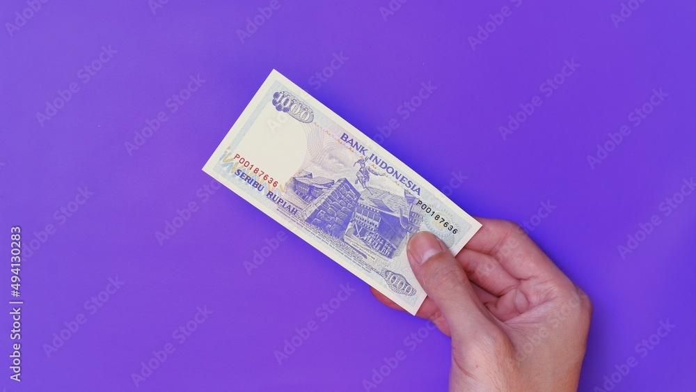 Indonesian Rupiah the official currency of Indonesia. Man's hand is ...