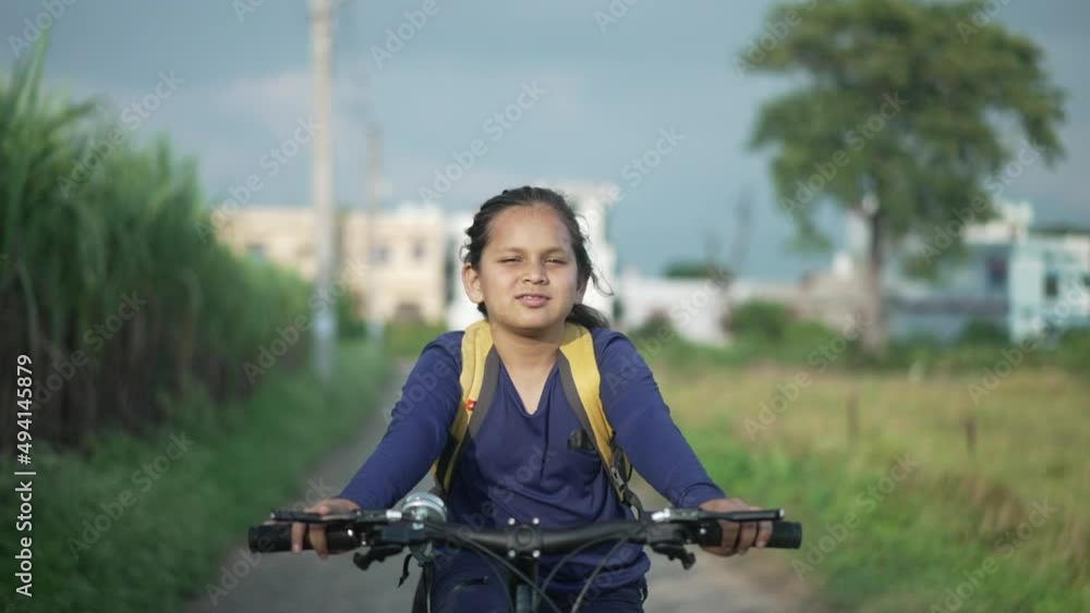 An Indian Kid cycling on a road, near a sugarcane field in a rural area ...