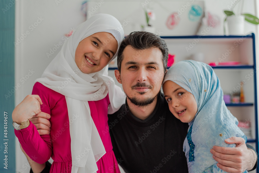 Happy Muslim family in the home. Young father hugging two child ...