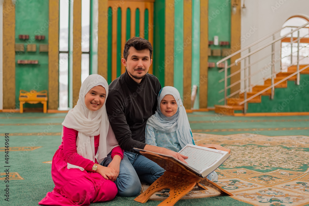 Happy Muslim family reading a holy book Quran. Father teaching child ...