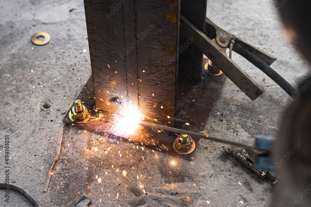 A welder is welding and installing a steel column structure on a steel ...