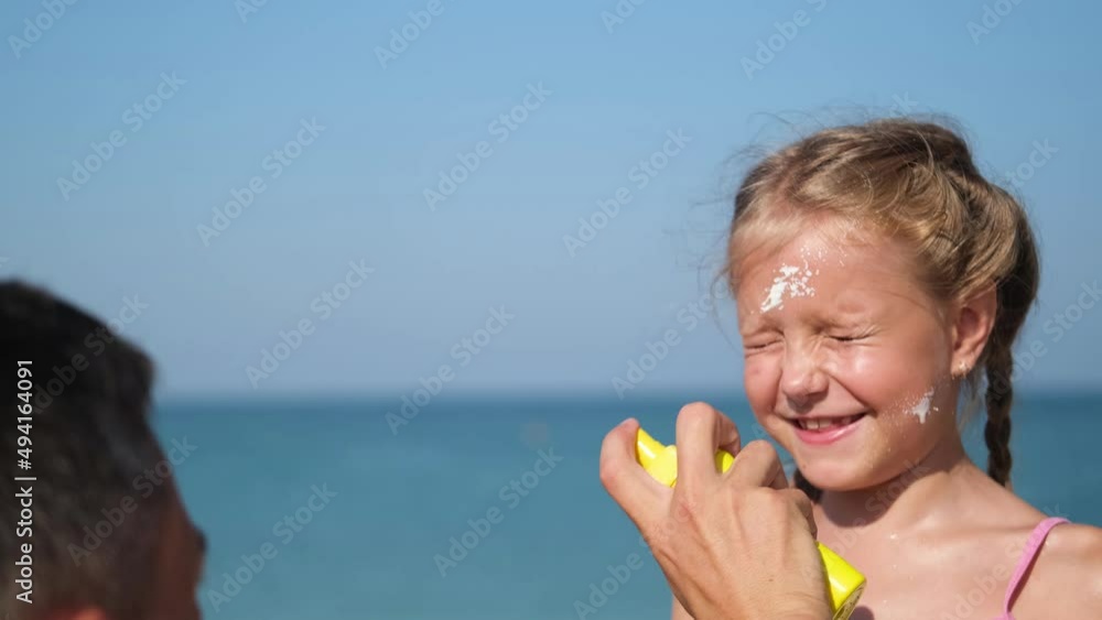 Father applying protective cream to her daughter's face at the beach ...
