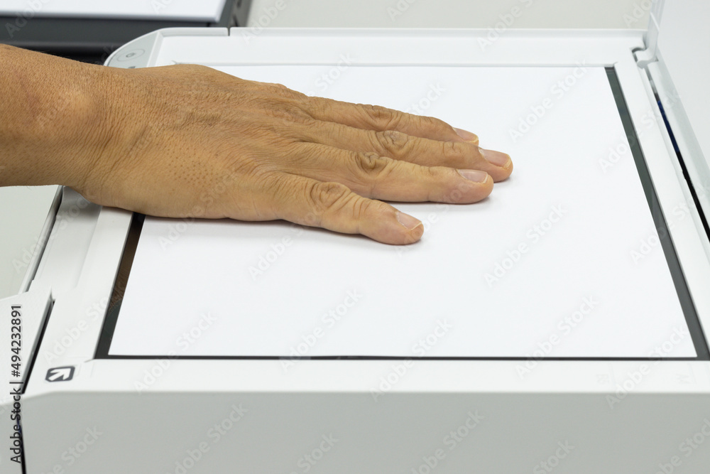 Hand holding a paper, inserting a scanner concept scanner for office ...