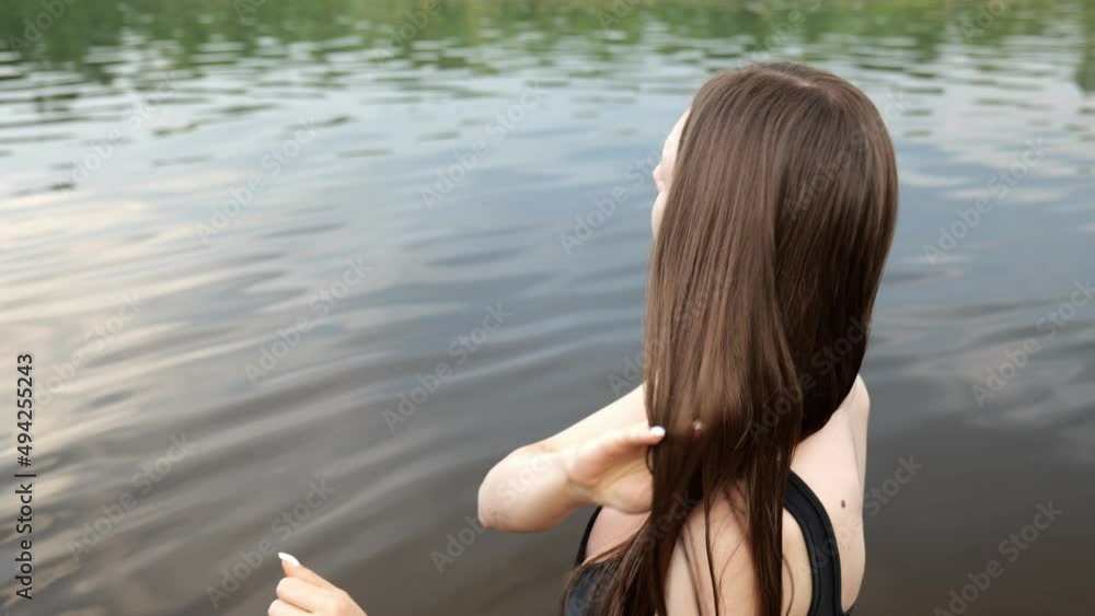 Side view of a girl with long hair in the water. Girl swim on nature in ...