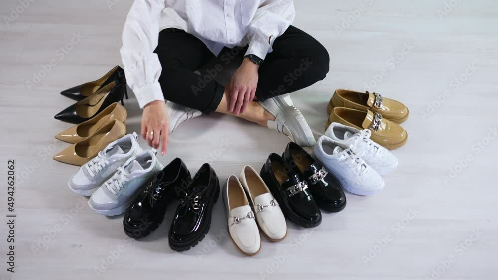 Woman sits on the floor with displayed footwear in front of her. Lady ...