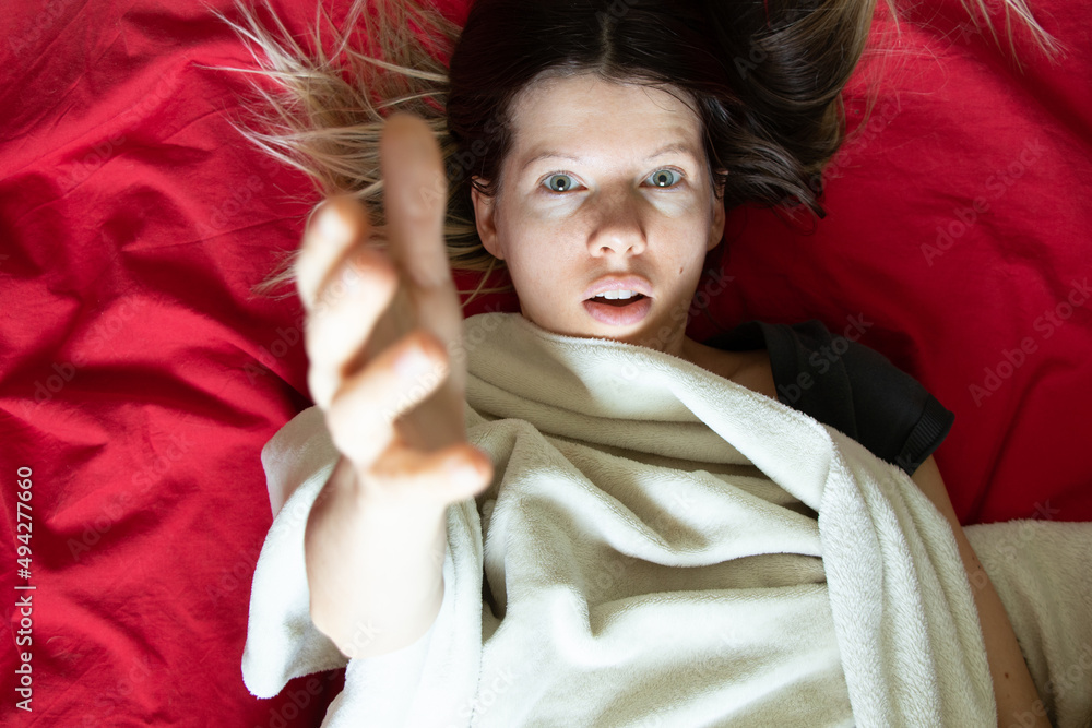 The girl lies in a bed on a red sheet and stretches her arms to the top ...