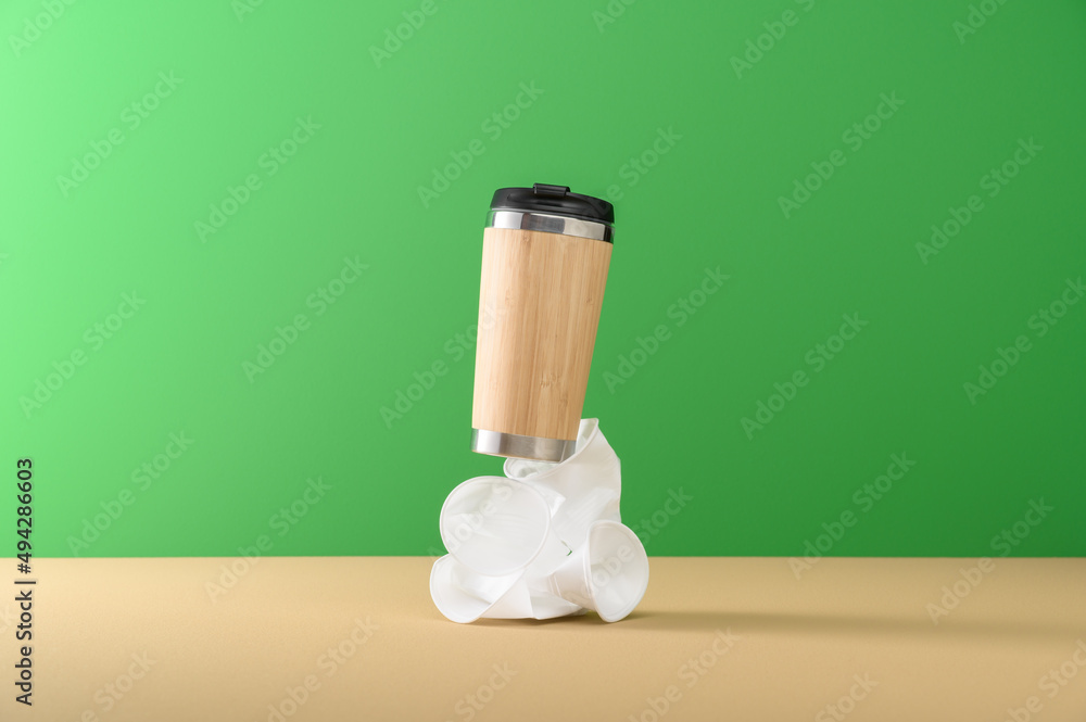 Poster Balancing reusable metal eco mug on crumpled disposable plastic ...