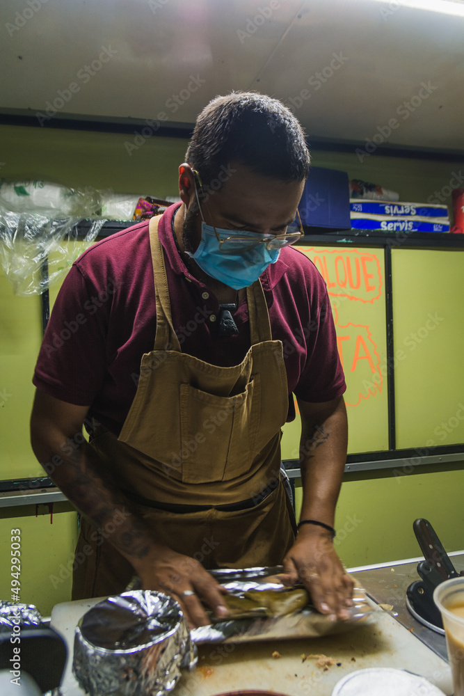 Mexican taquero at his typical stand preparing the meat and tortillas ...