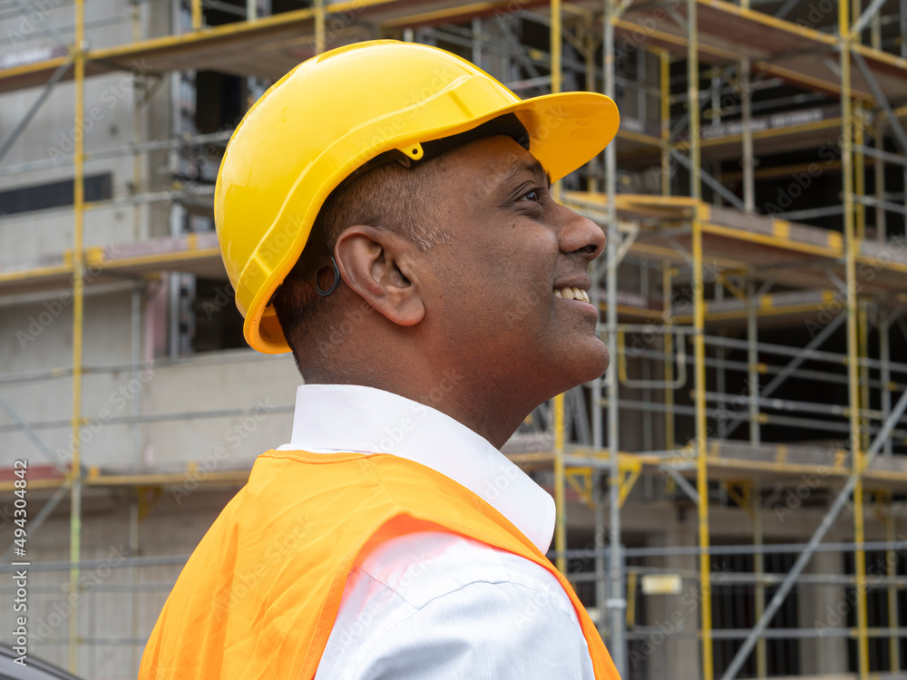 Profile portrait of a smiling Indian engineer or factory worker wearing ...