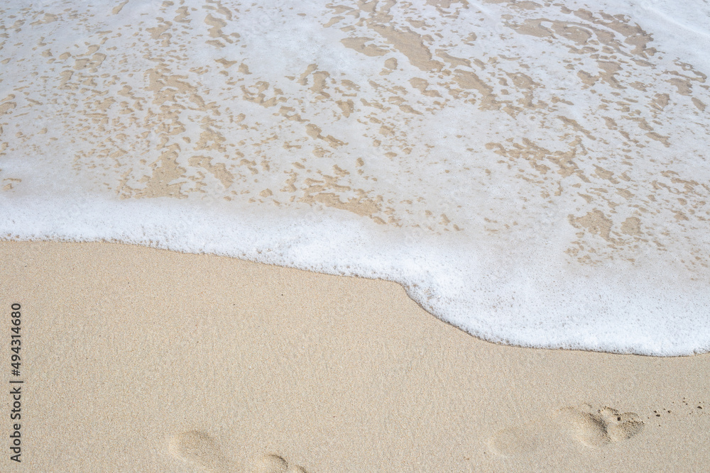 Sandy shore with footprints, an oncoming sea wave. Natural background ...