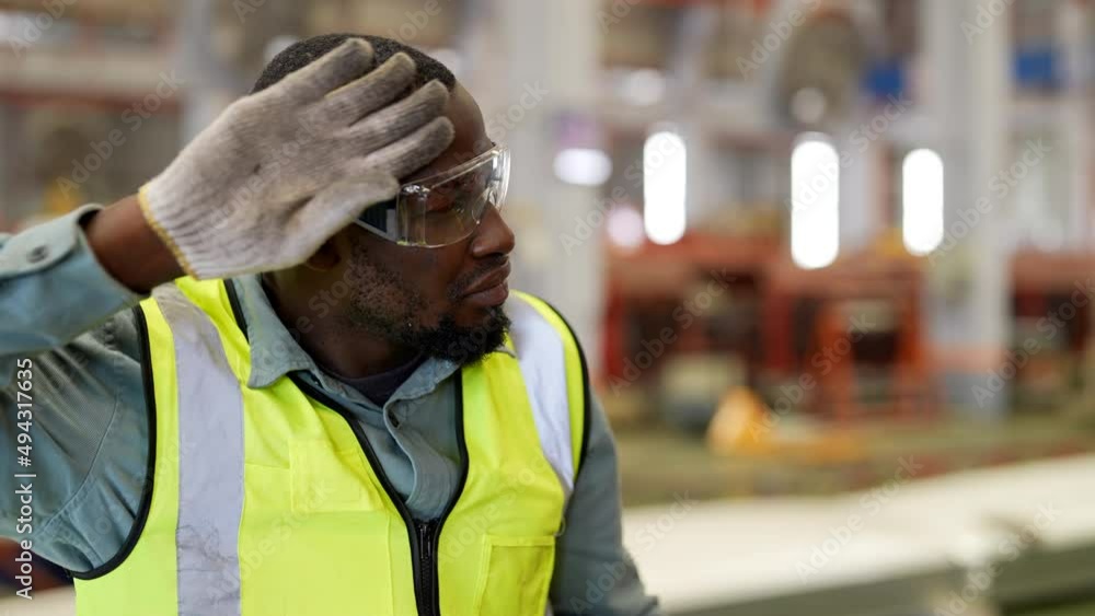 Tired black industrial engineer worker wiping the sweat away from ...