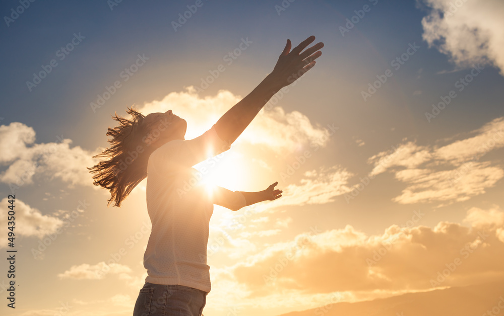 Freedom and hope. Woman raising her arms up to the light golden ...