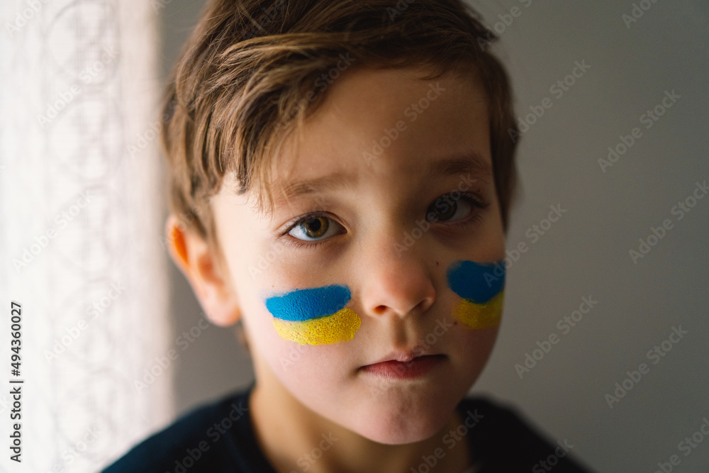 Portrait of a Ukrainian boy with a face painted with the colors of the ...