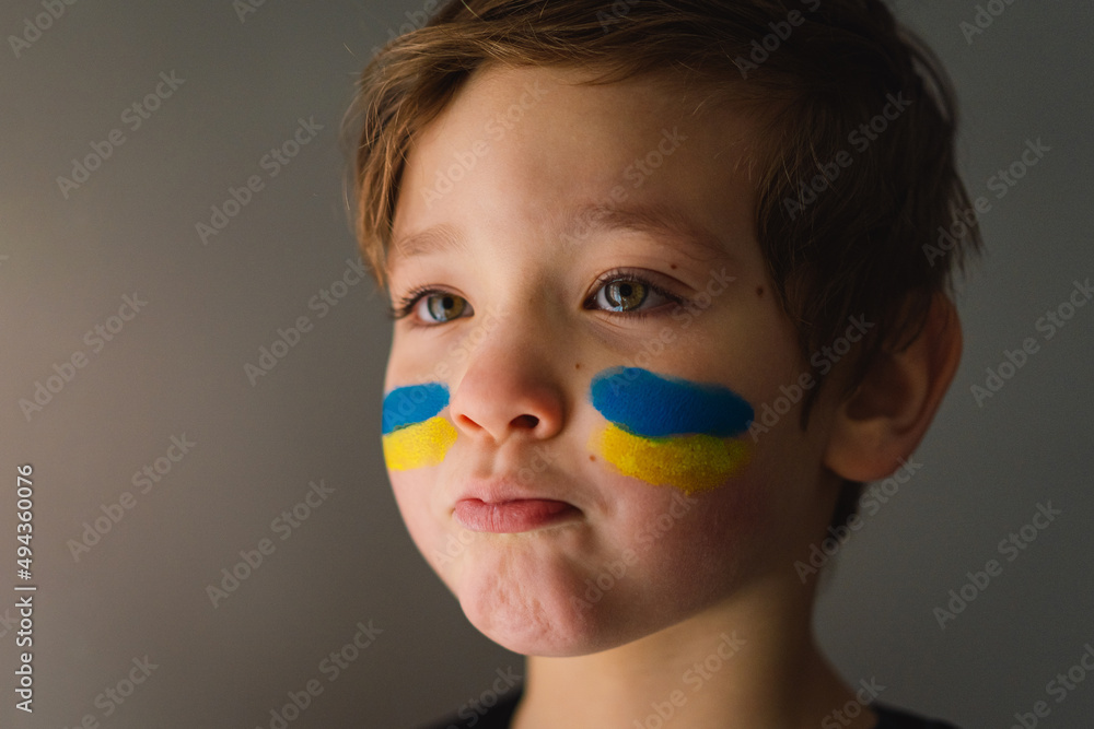 Portrait of a Ukrainian boy with a face painted with the colors of the ...