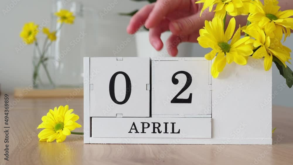Spring month April 2. A woman's hand turns over a cubic calendar. White ...