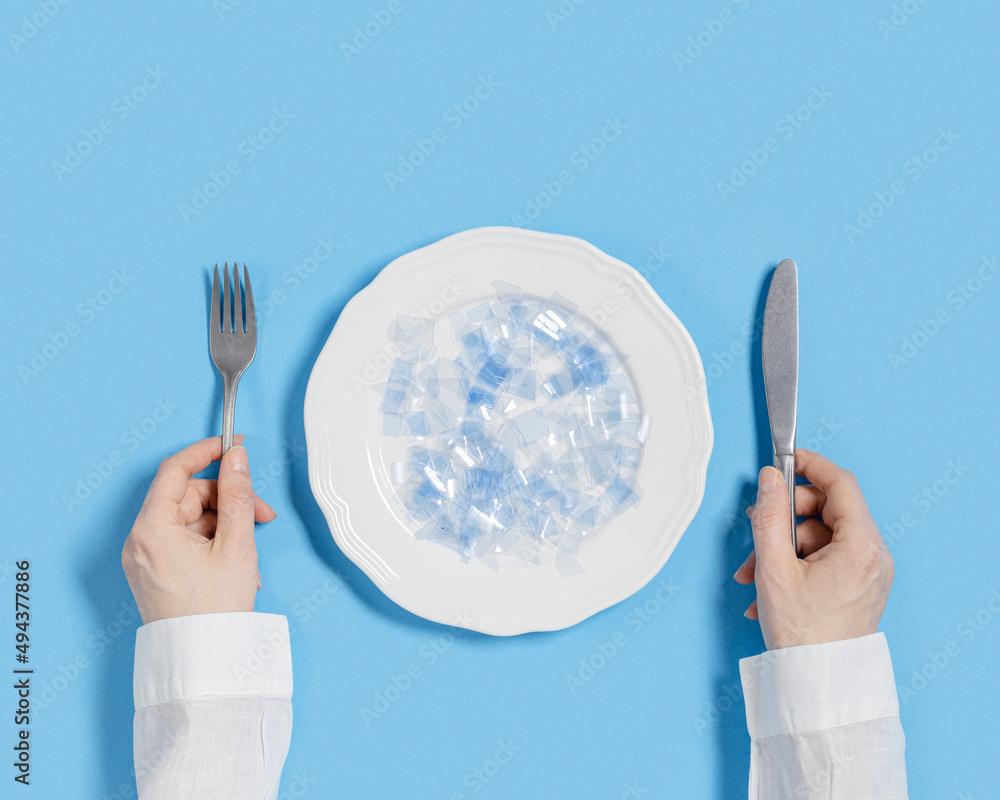 Plate with microplastics as food on blue background. Plastic pollution ...