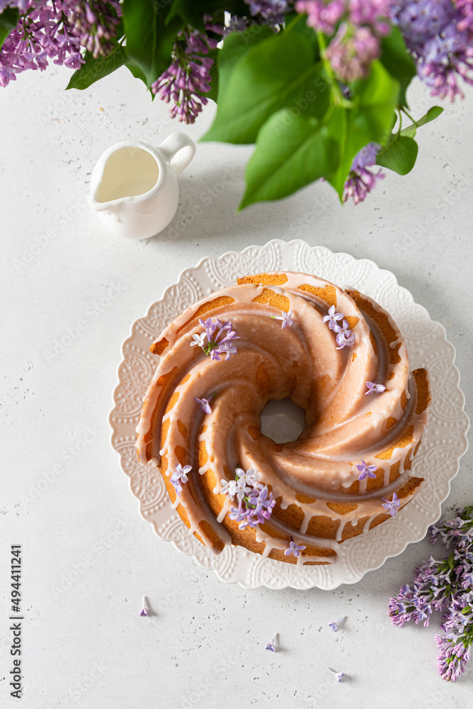 Classic Vanilla Bundt Cake with Sugar Glaze and lilac flowers on white ...