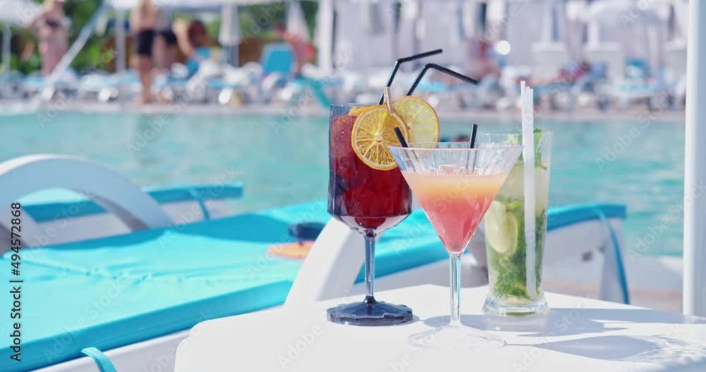 Three glasses of colorful alcoholic cocktails with straws standing on ...
